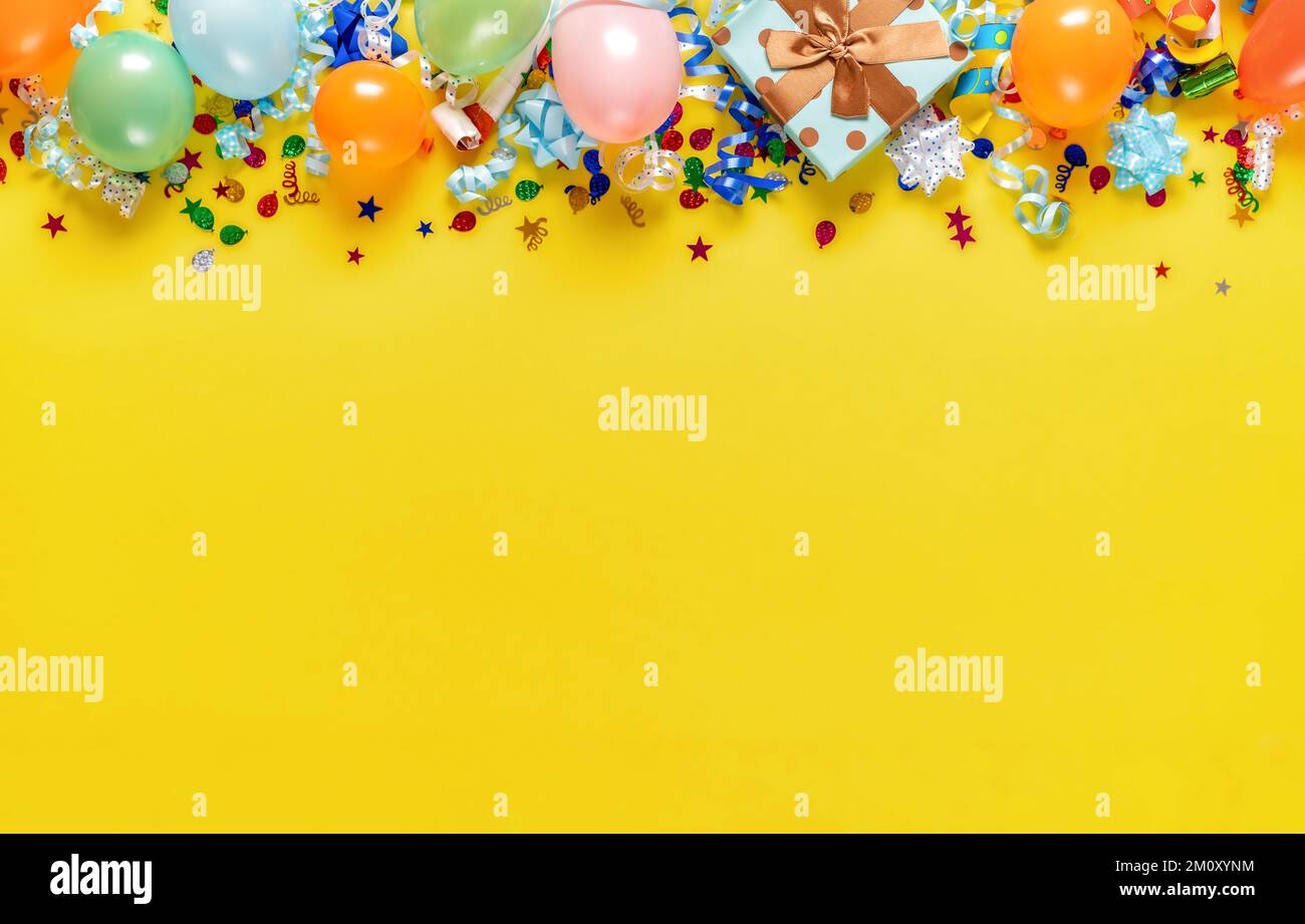 Balloons and various party decorations on a yellow background with copy ...