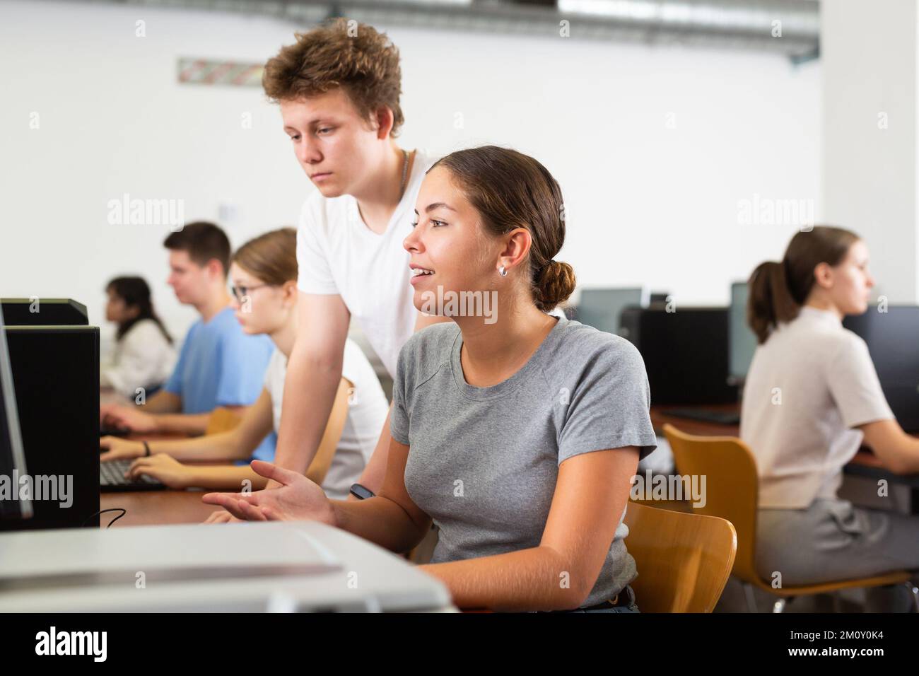 Schoolboy using computer and teacher helping to him in class room Stock ...