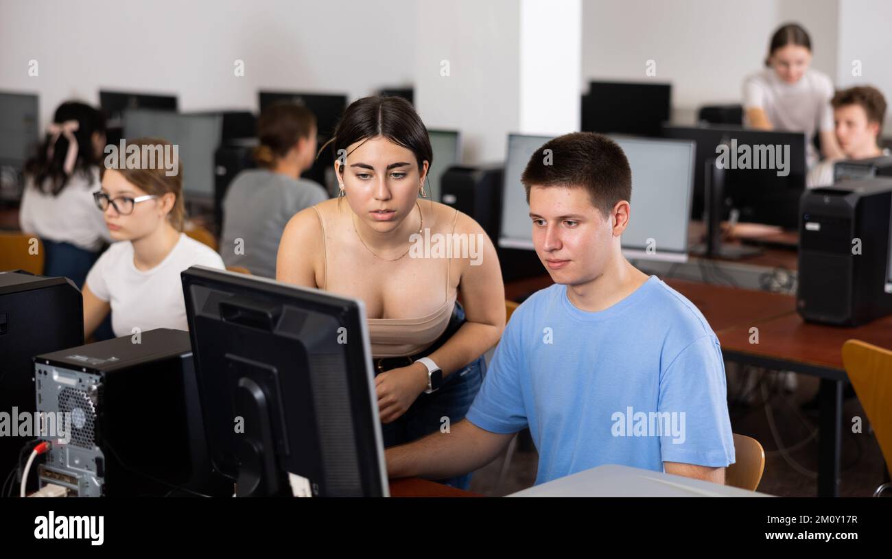 Smart female teenager giving a clue to the male classmate while she is ...