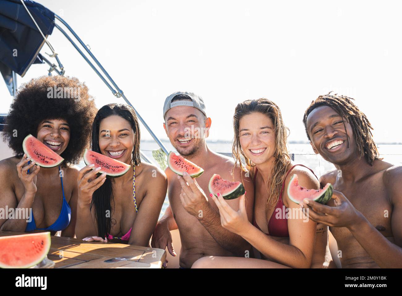 Group of young friends relaxing on luxury yacht, having fun together and eating healthy fruit on ...