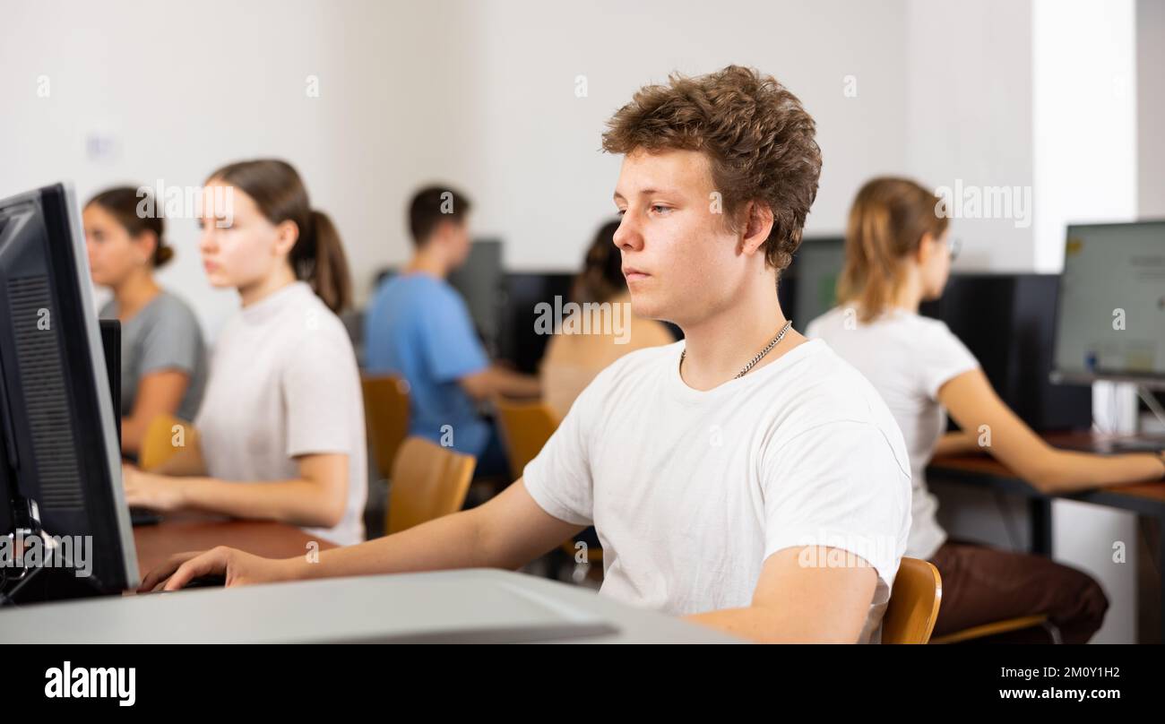 Positive male student using PC and studying computer science in the ...