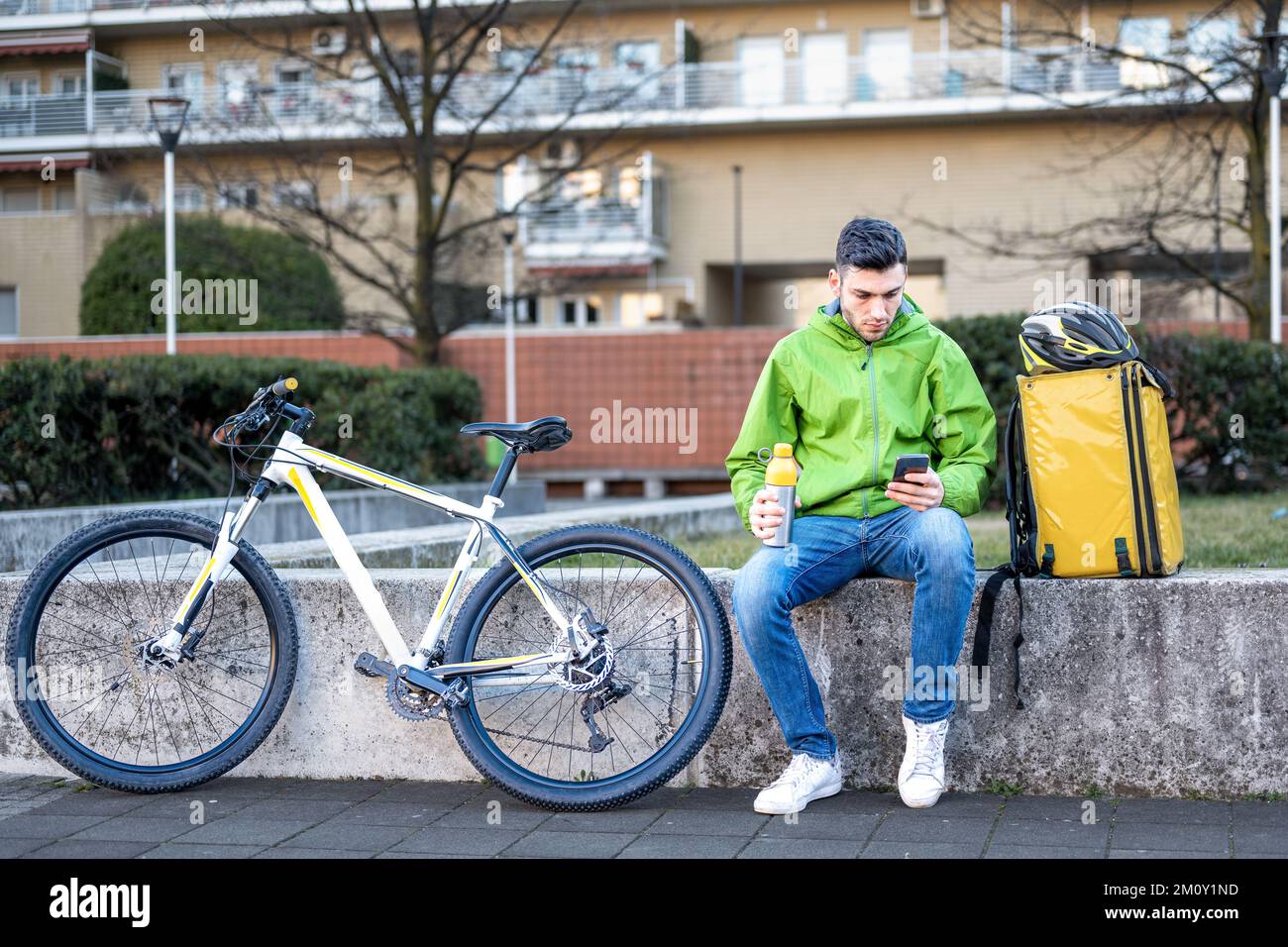 Delivery man having a break, young rider using mobile application and ...