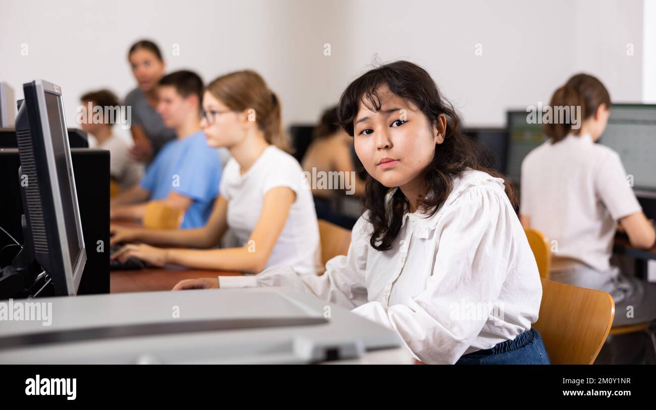 Portrait of fifteen-year-old schoolgirl studying at computer in class ...