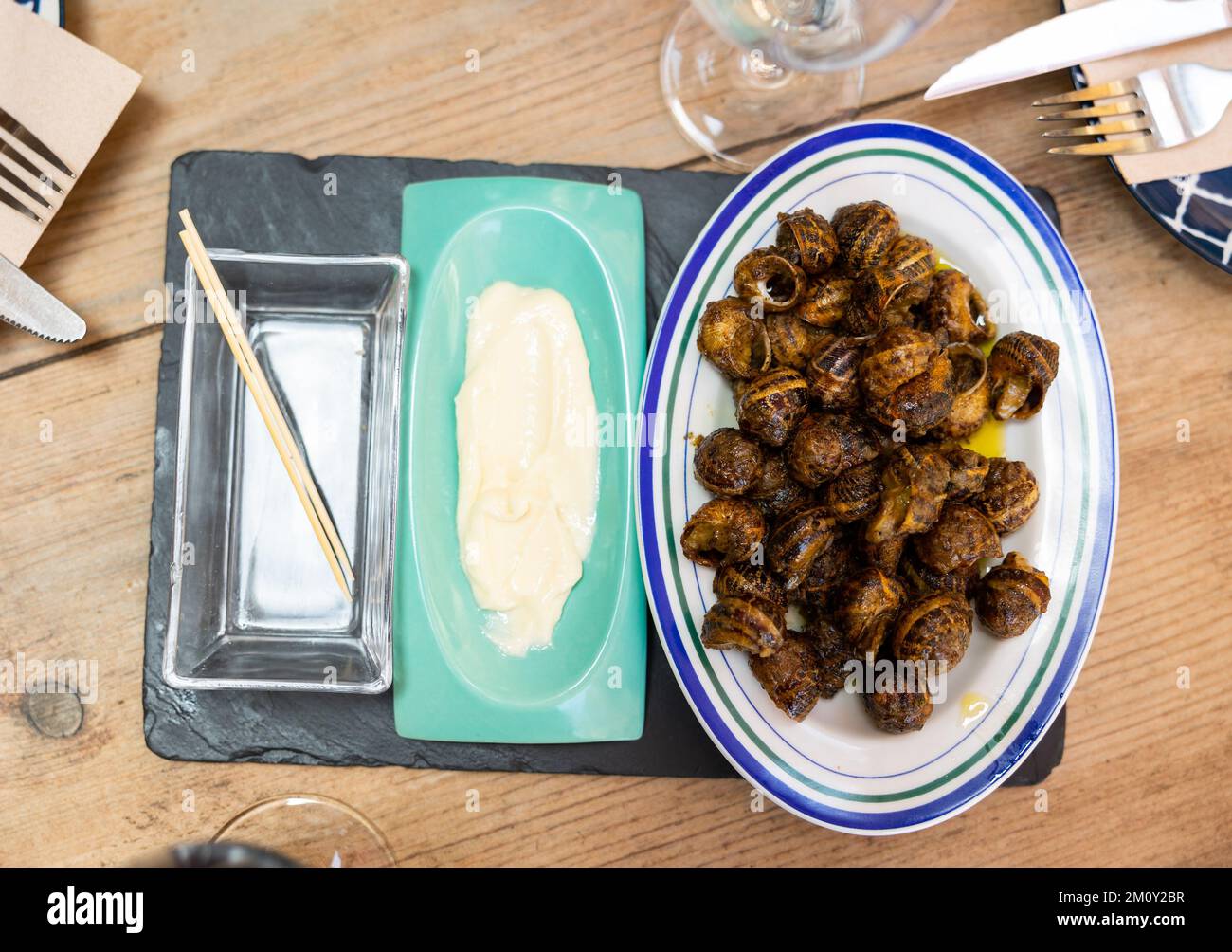 Plate of Caracoles cooked in shells on grill aioli sauce Stock Photo ...