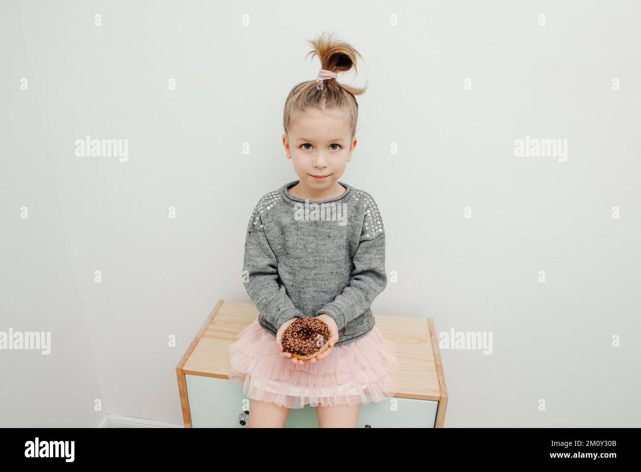 Cute little girl with funny hairstyle is sitting on the commode with ...