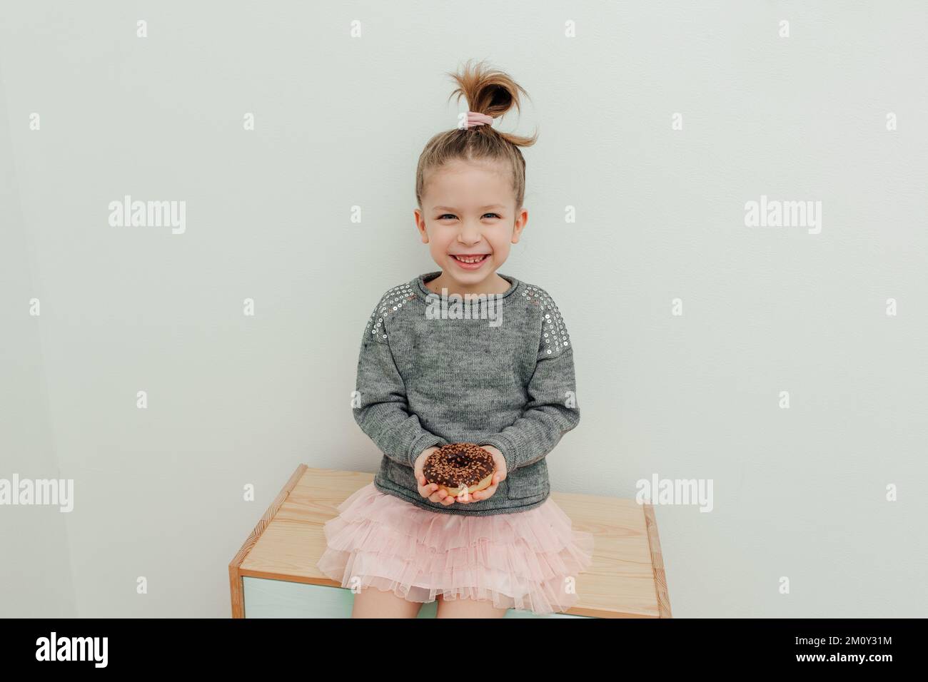 Funny little girl with modern hairstyle is sitting on the commode with ...