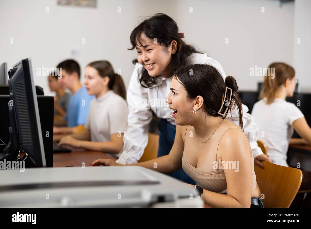 Positive teenage girls using computer in classroom Stock Photo - Alamy