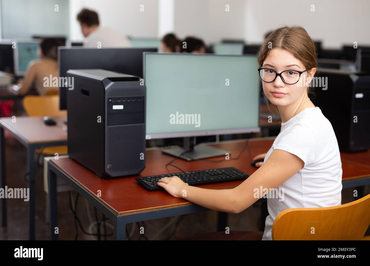 Focused female student in glasses using PC and studying computer ...