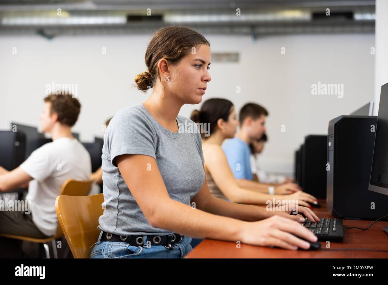 Side view on focused teenager female student sitting at desk in ...