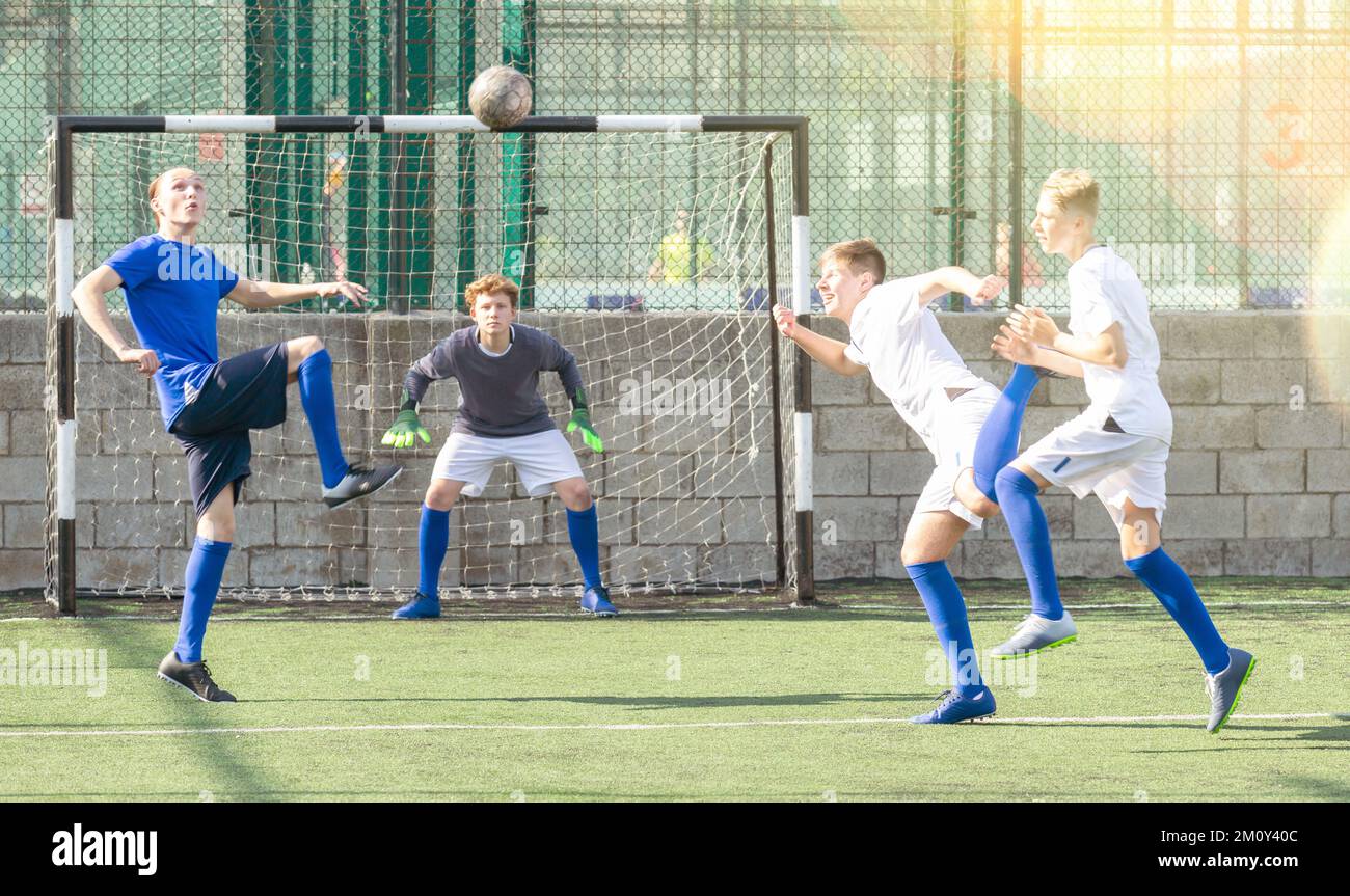 Game of football match between two teams of teenagers in white and blue ...