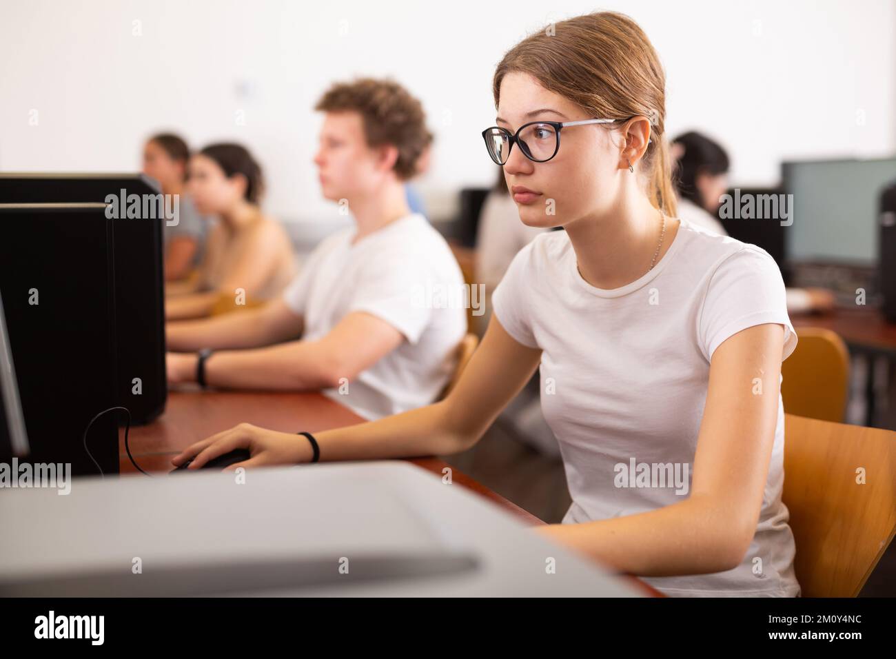 Portrait of interested teen girl during lesson in computer room of ...