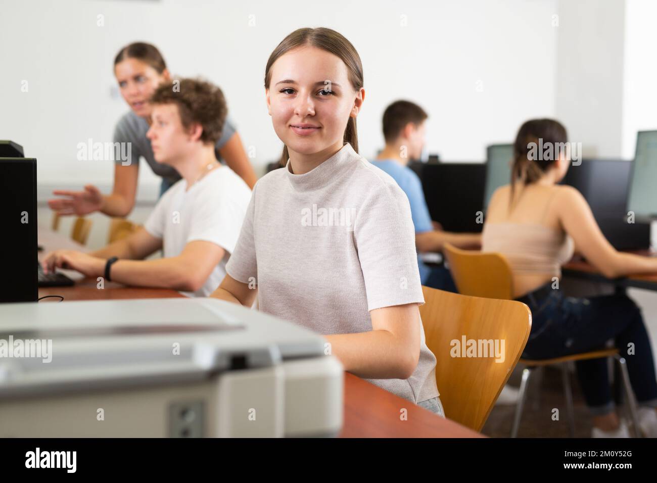 Smiling female student using PC and xerox while studying computer ...