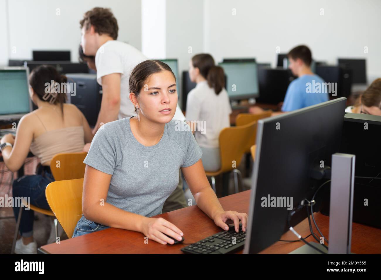 Teacher works at computer in the classroom. Students doing programming ...