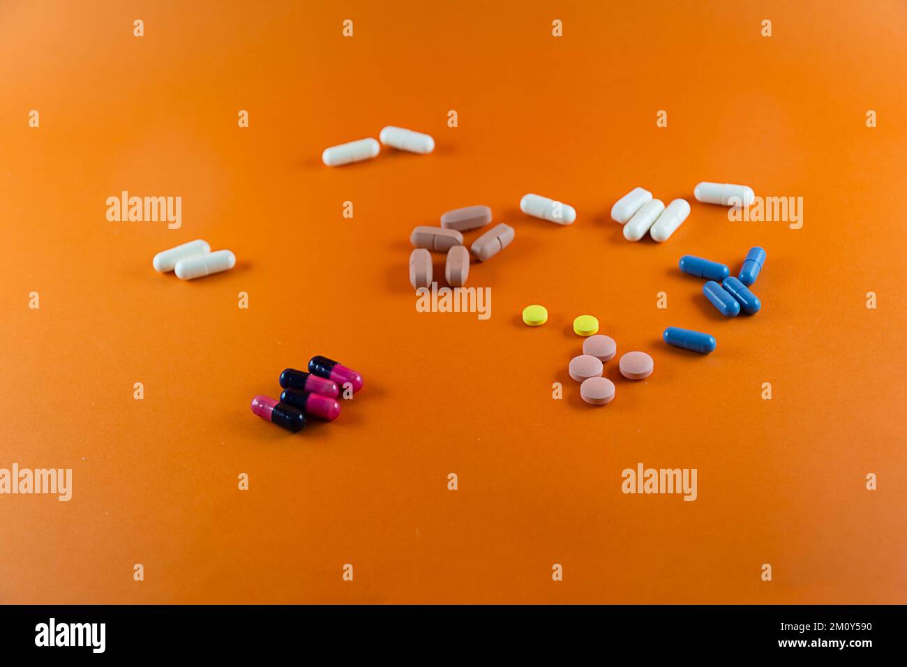 Different pills scattered on an orange background. Medical supplies ...