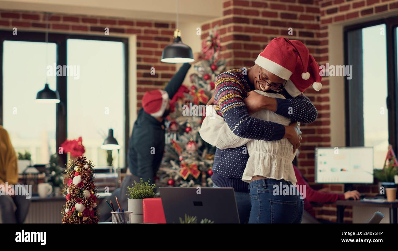 Colleagues with santa hats exchanging presents during xmas eve, giving christmas gifts to ...
