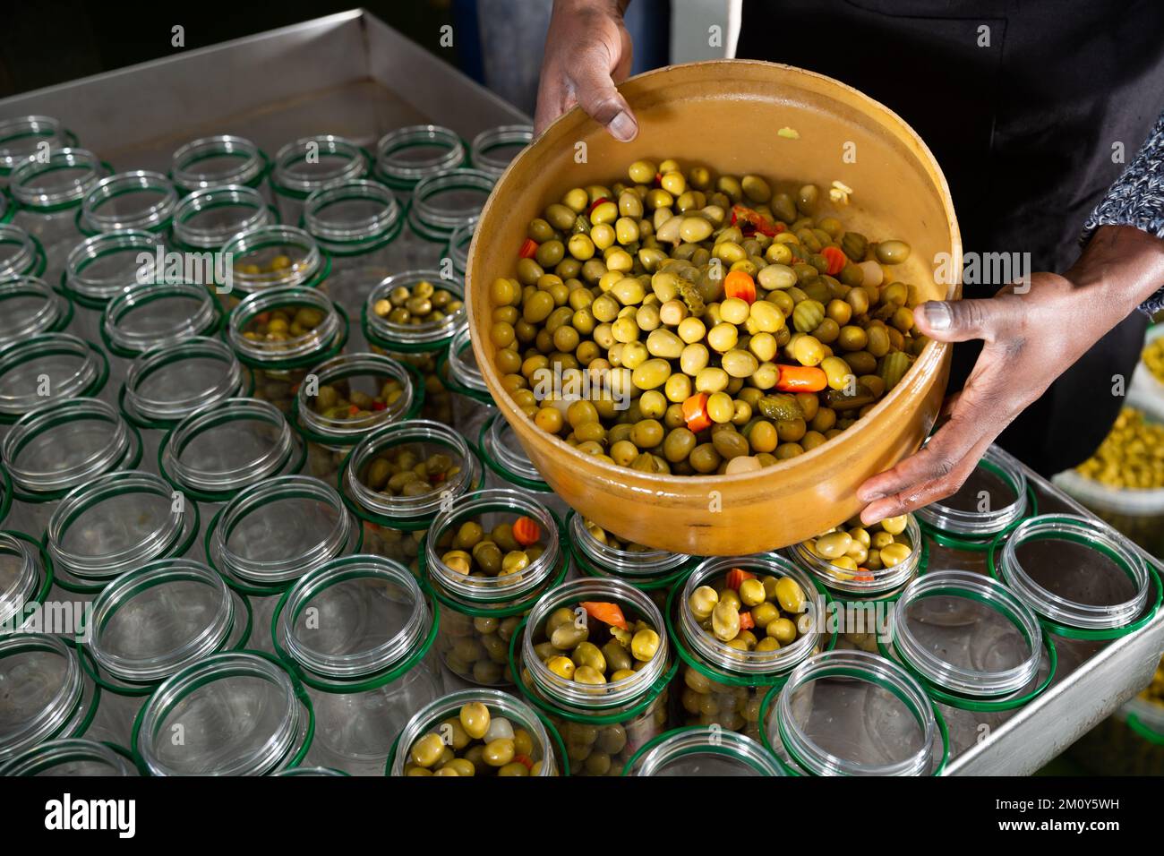 Filling glass jars with olives for pickling Stock Photo - Alamy
