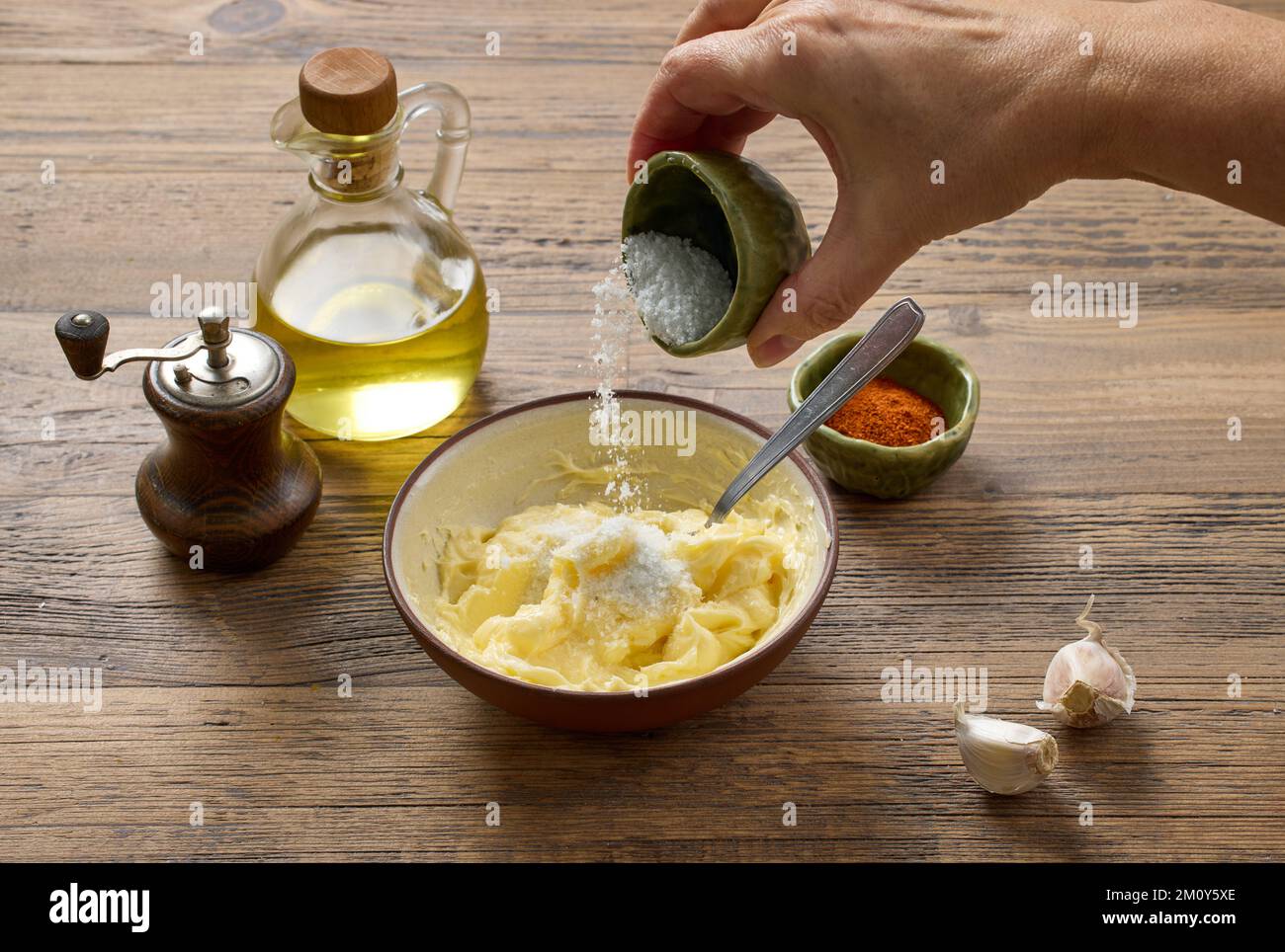 adding salt to bowl of whipped butter. garlic butter ingredients on ...