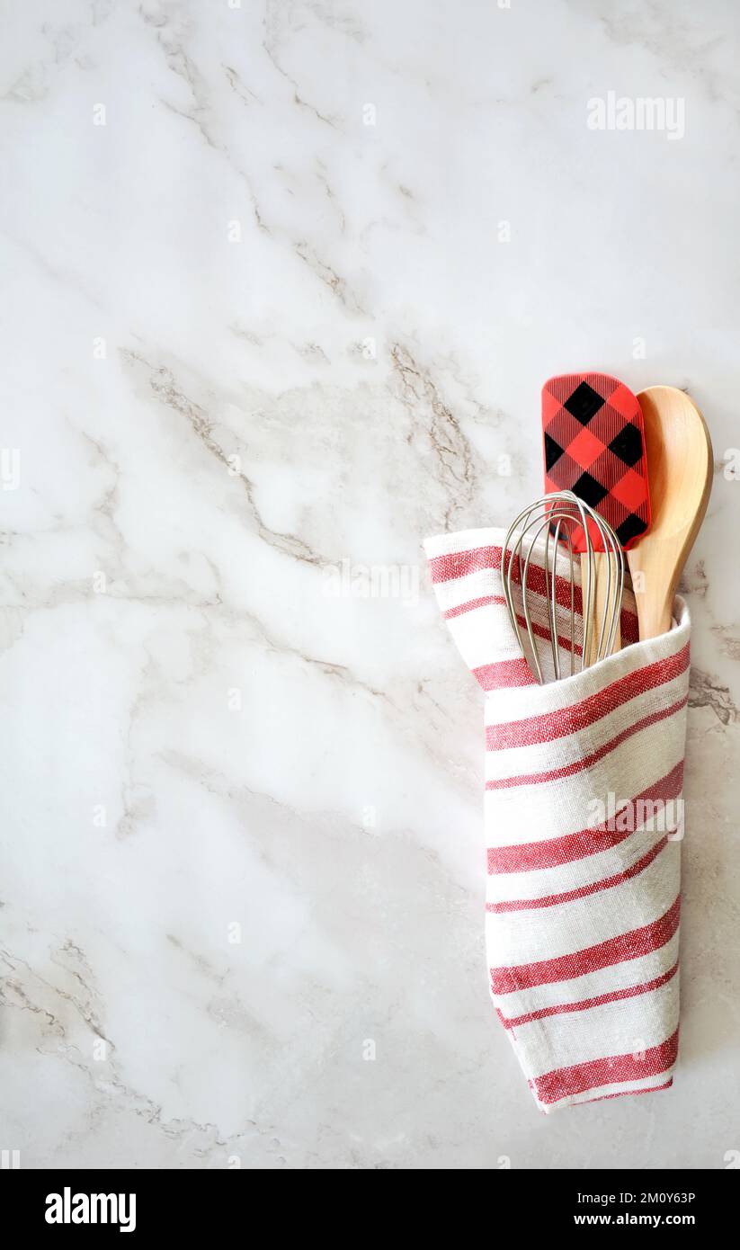 Spatula,wooden spoon,and whisk wrapped in red and white tea towel on ...