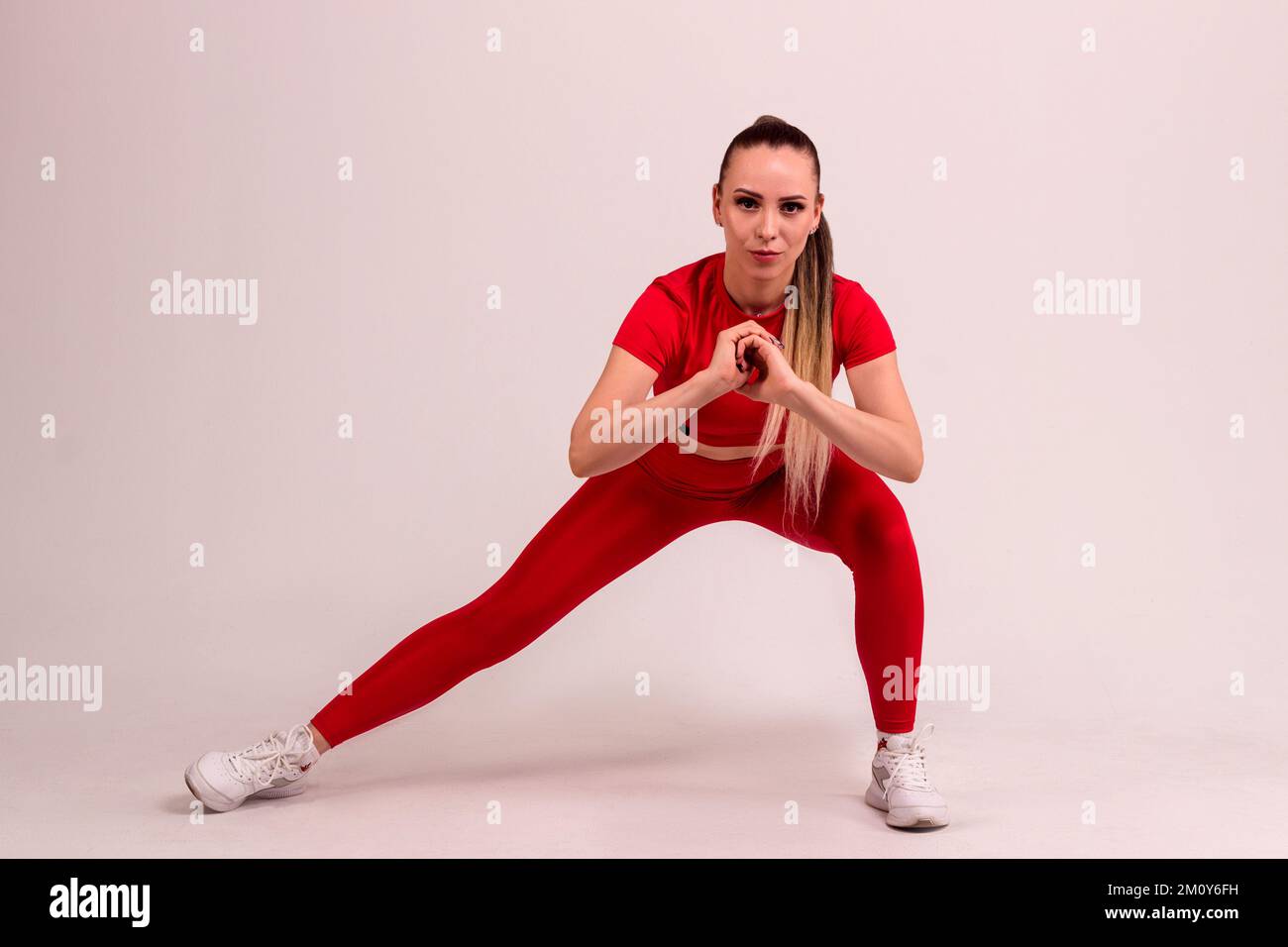 A young woman in a red tracksuit goes in for sports on a white ...