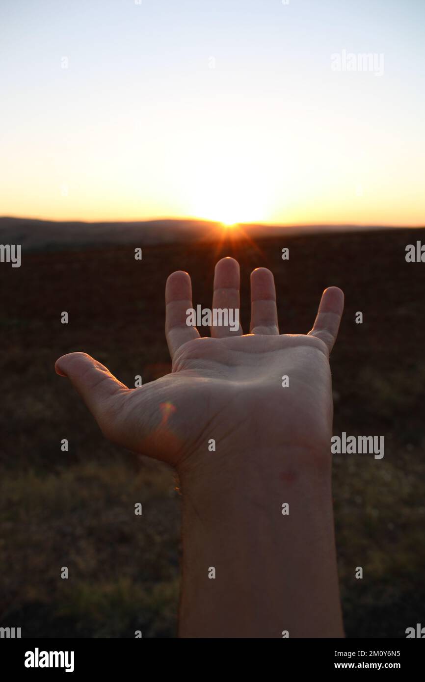 A thin road with long paths between fields. hand of a man. Asking for ...