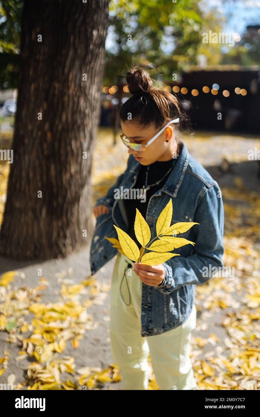 A woman in an autumn park holds a yellow leaf Stock Photo - Alamy