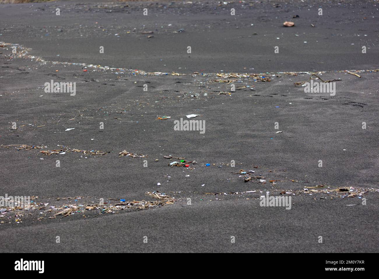 Trash in the sand, plastic waste by the ocean, sad and unsustainable ...