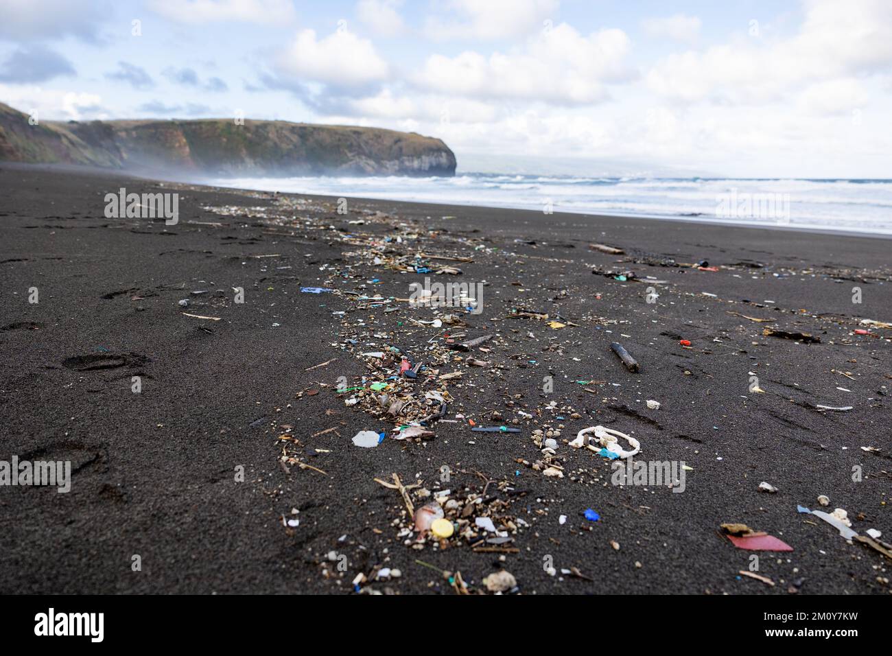 Trash in the sand, plastic waste by the ocean, sad and unsustainable ...