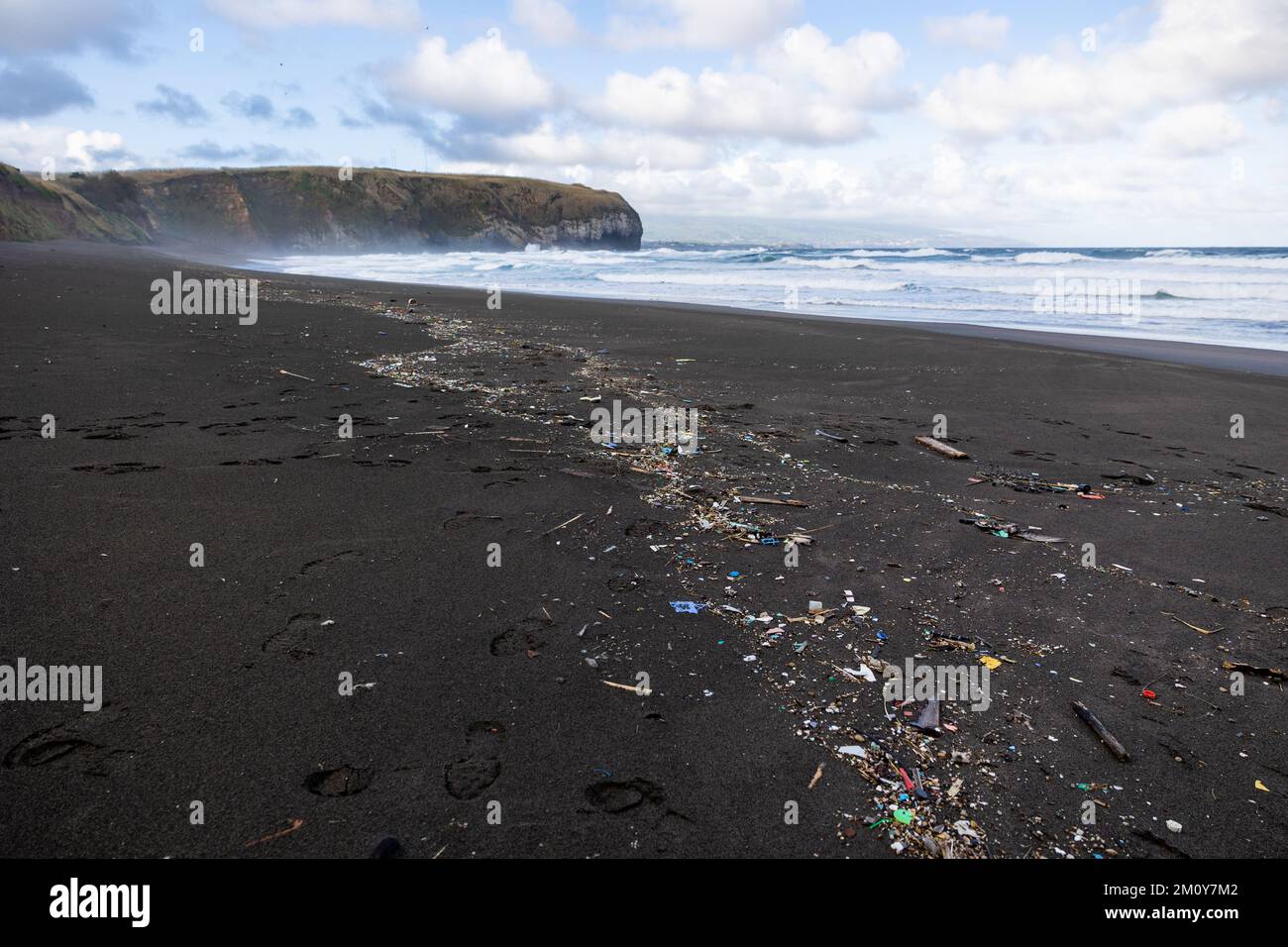 Trash in the sand, plastic waste by the ocean, sad and unsustainable ...