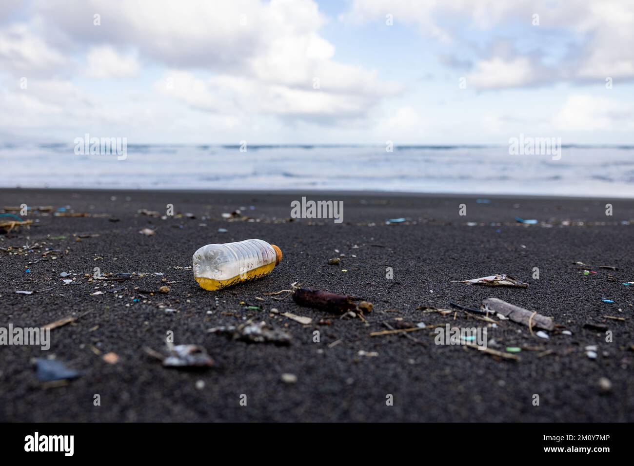 Trash in the sand, plastic waste by the ocean, sad and unsustainable ...