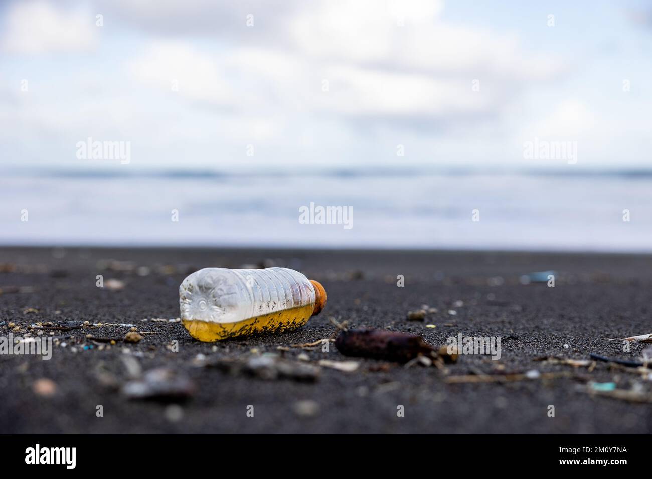 Trash in the sand, plastic waste by the ocean, sad and unsustainable ...