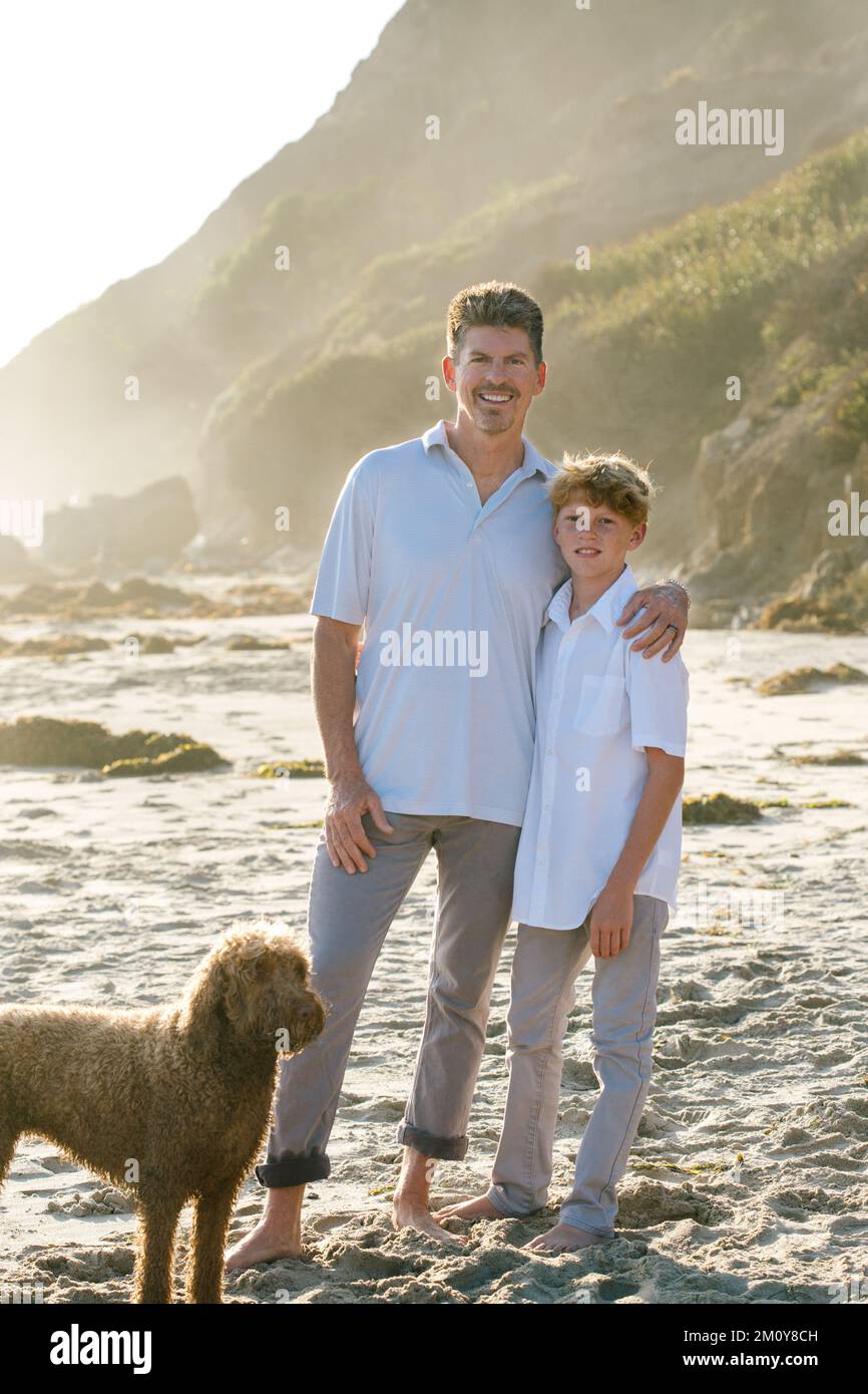 Father And Son Stand On Beach With Labradoodle Stock Photo - Alamy