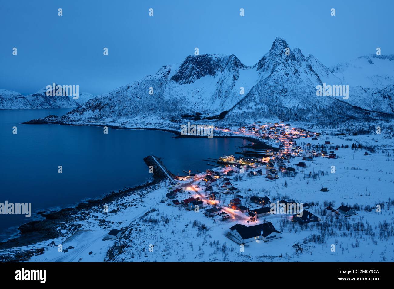 Village lights of Mefjordvær shine in winter twilight, Senja, Norway ...