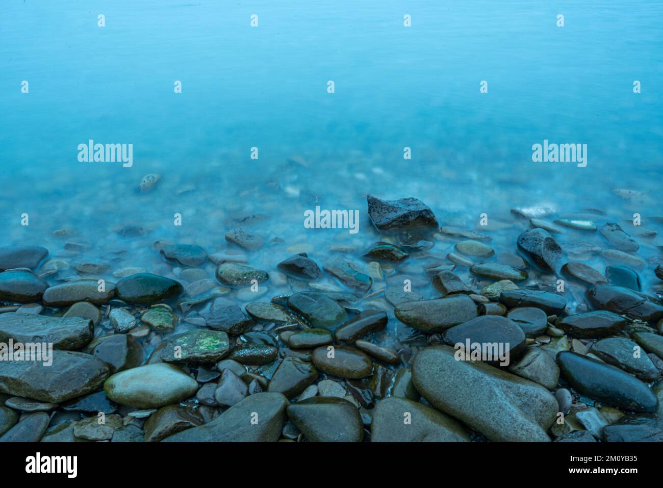 Pebble stones on the shore close up in the blurry sunset light in the ...