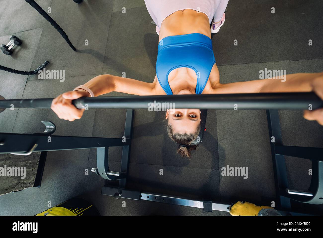Beautiful woman doing exercises with barbell on a bench press training ...