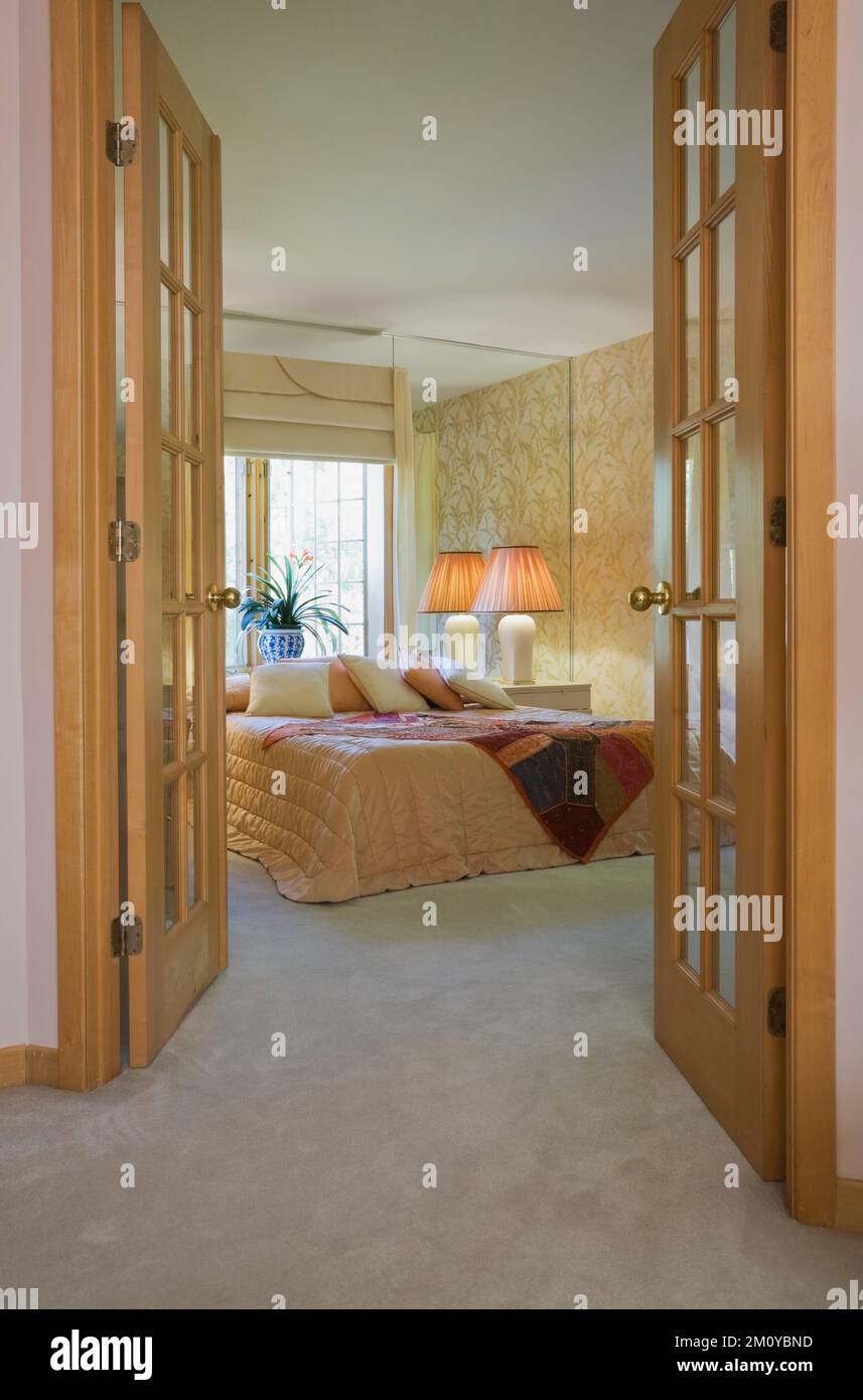 King size bed in master bedroom with large wall mirror through opened ...