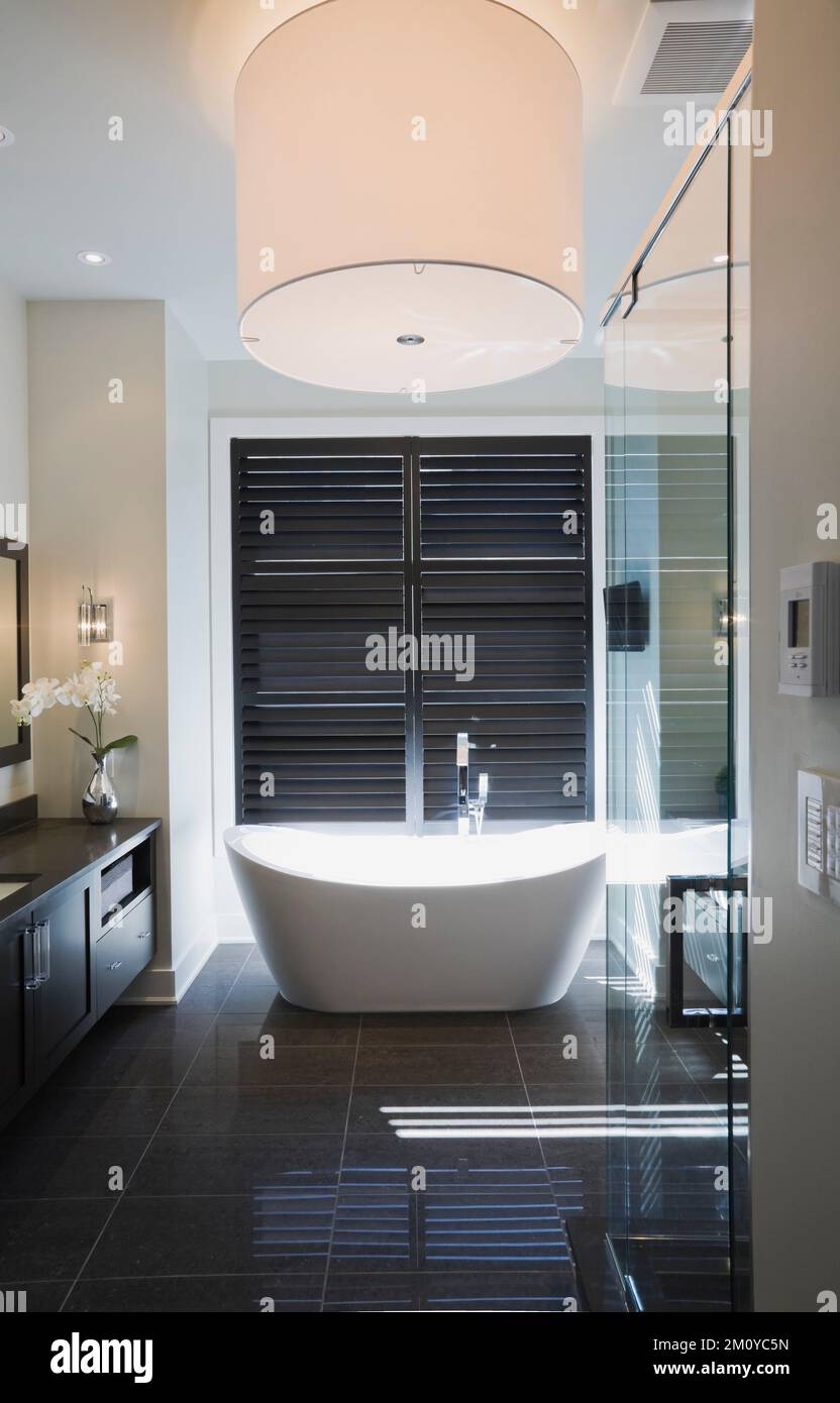 Large white round shaped lighting fixture over freestanding bathtub in ...