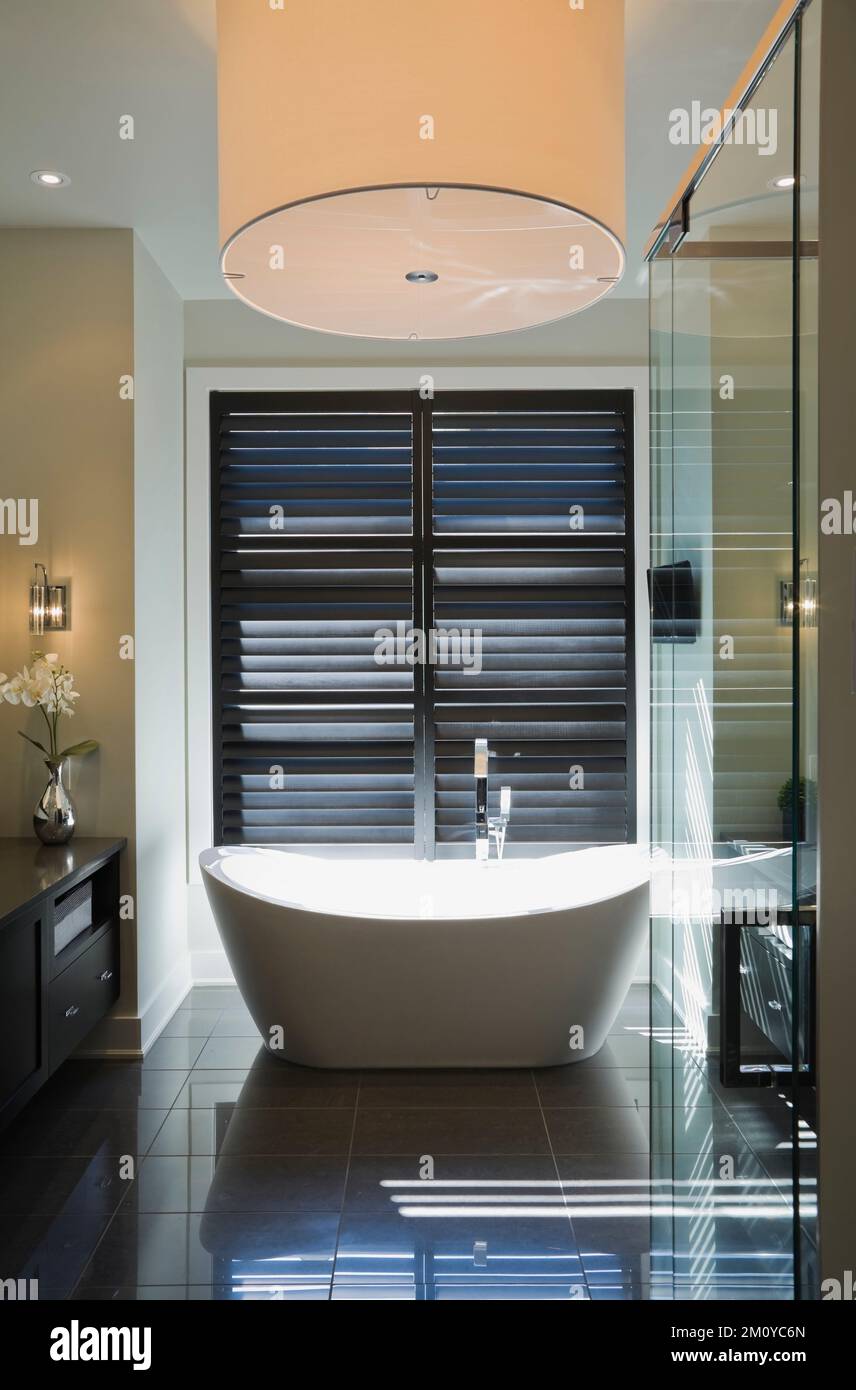 Large white round shaped lighting fixture over freestanding bathtub in ...