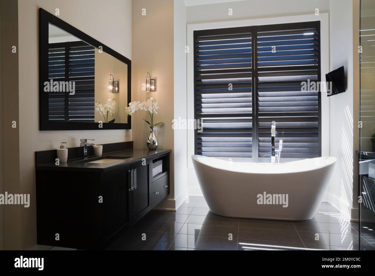 White freestanding bathtub and black vanity in opulent bathroom inside ...