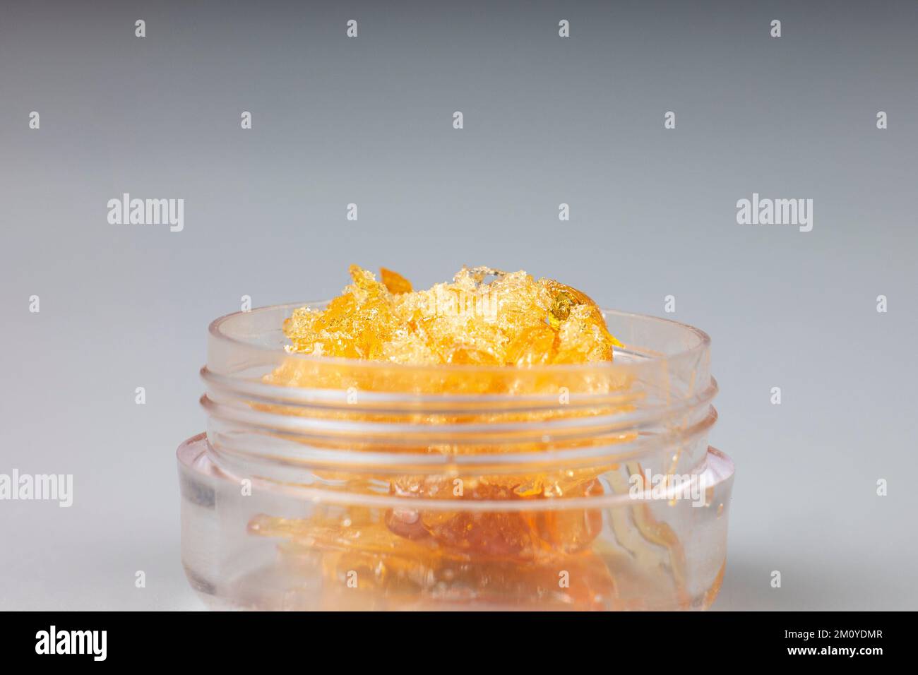 glass jar with golden cannabis wax, pieces of hardened resin of ...