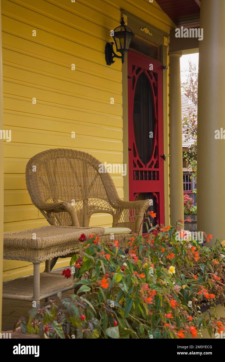 Wicker armchair and table on veranda of old yellow 1850 Canadiana ...