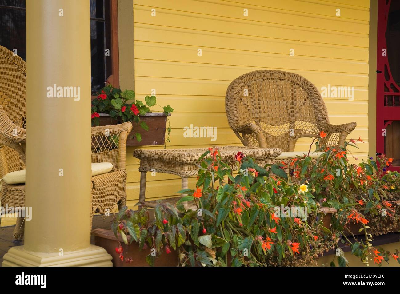 Wicker armchairs and table on veranda of old yellow 1850 Canadiana ...