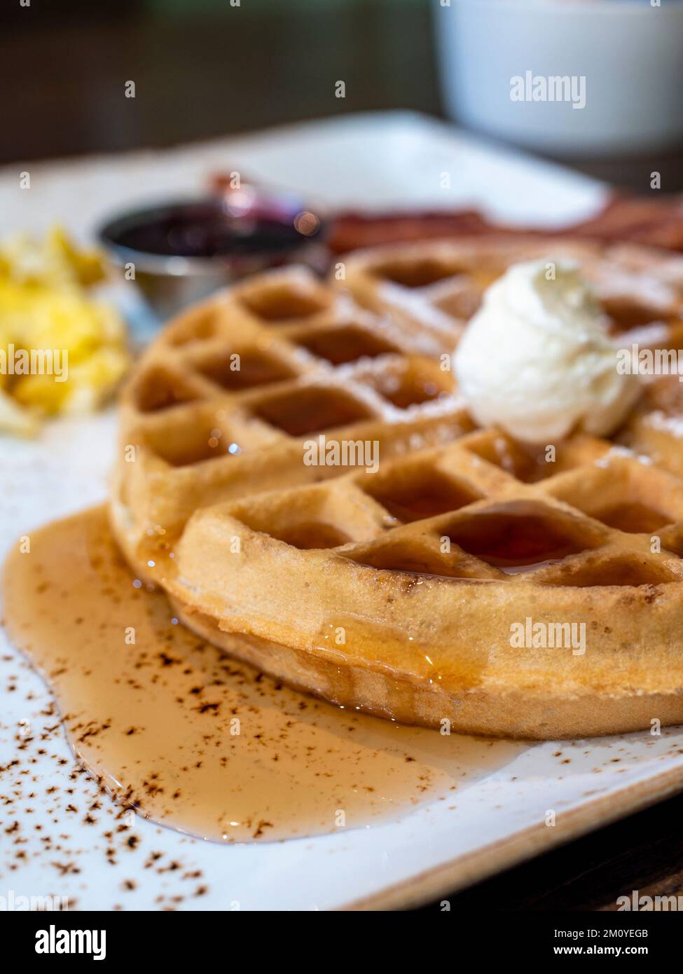 American breakfast with a Belgian waffle, scrambled eggs and bacon on a ...