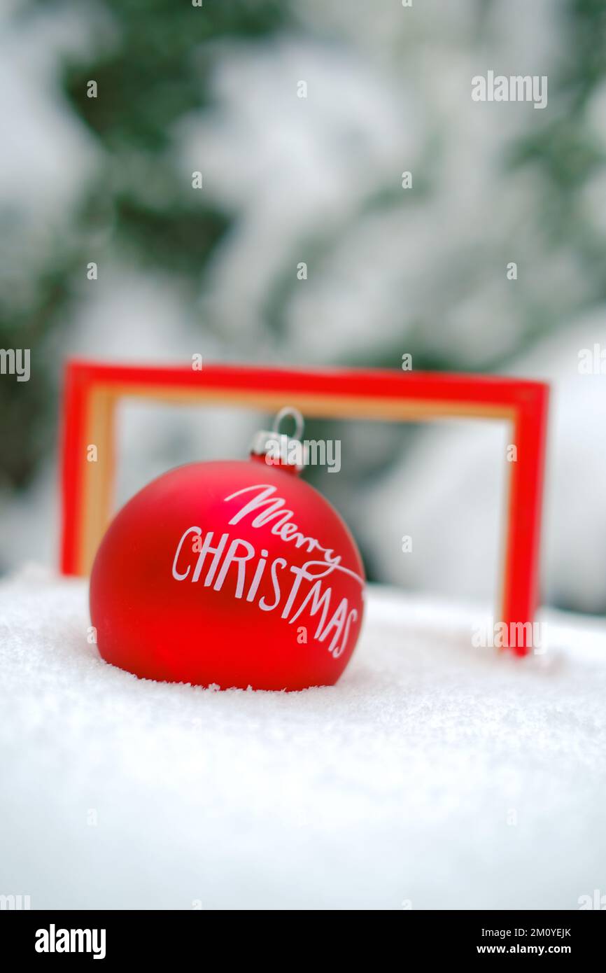 Merry Christmas .Red Christmas decorative ball in a frame in the snow ...