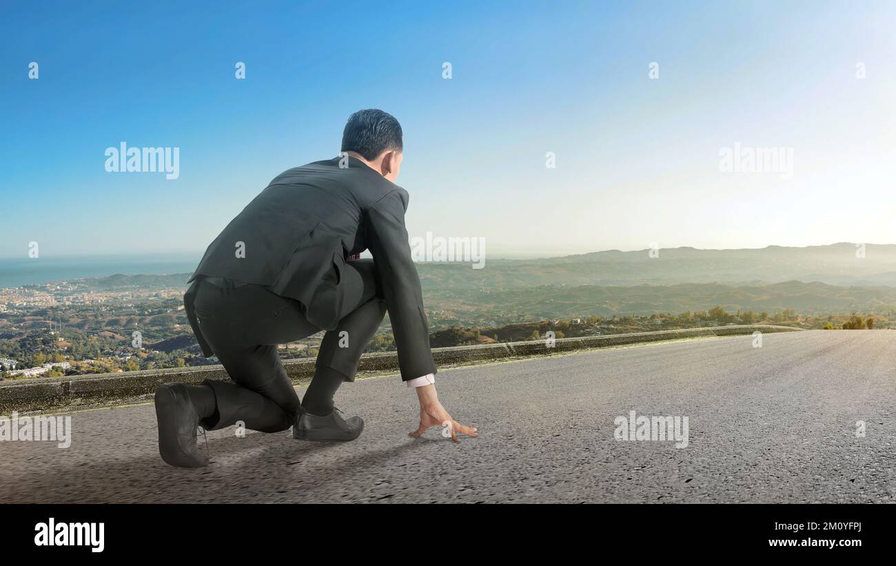 Rear view of Asian businessman in start position ready to run with blue ...
