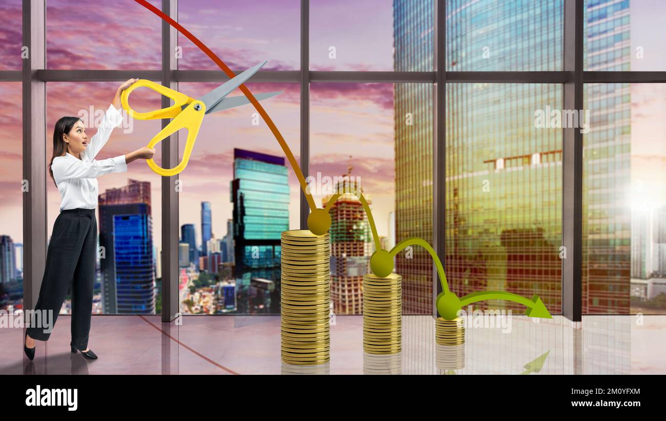 Asian businesswoman holding scissors to cut decrease arrow on the coin ...