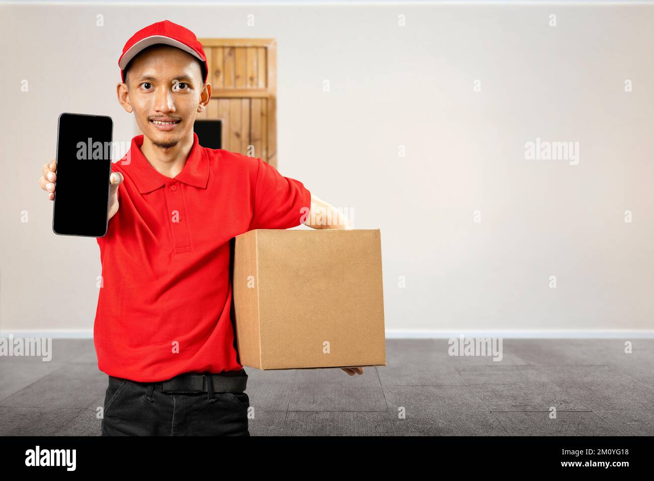 Parcel delivery man with a hat showing his mobile phone screen while ...