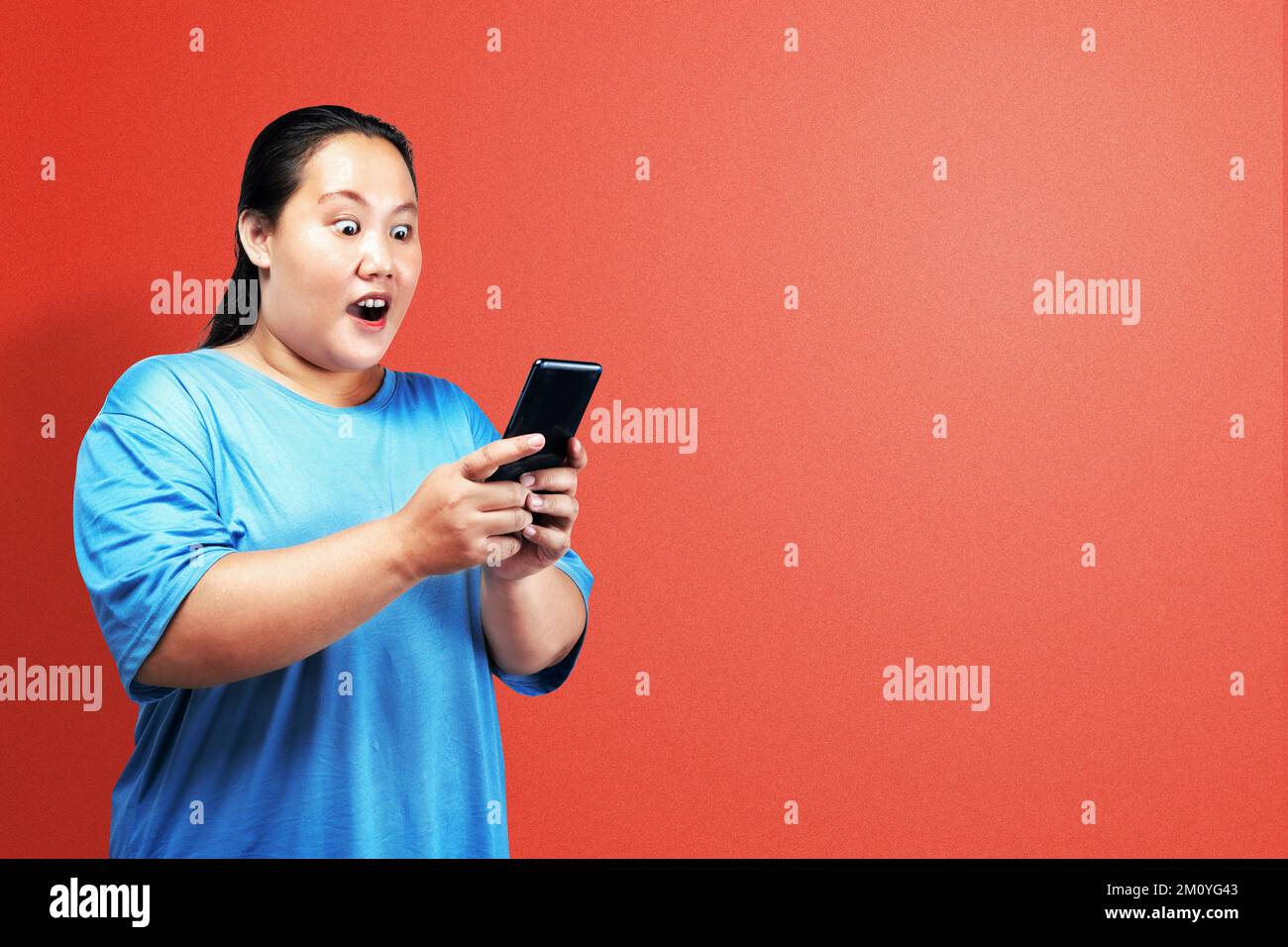 Asian fat overweight woman holding a mobile phone with a shocked ...