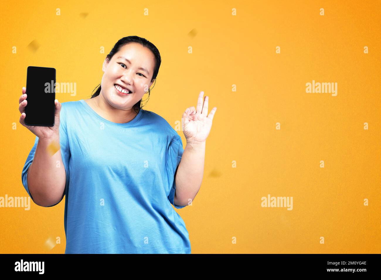 Asian fat overweight woman holding a mobile phone and showing an empty ...