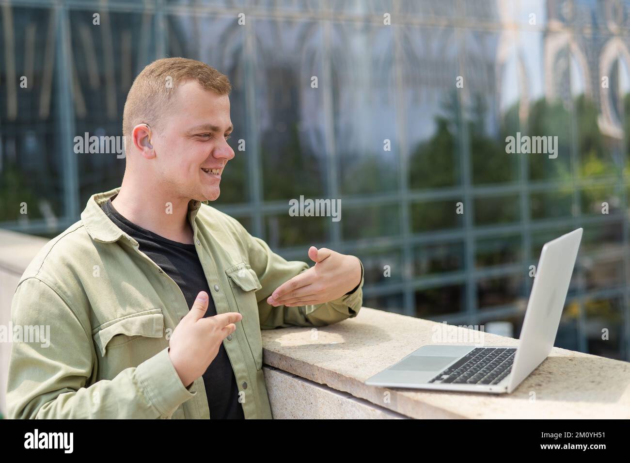 Caucasian man communicates in sign language via video link on laptop ...