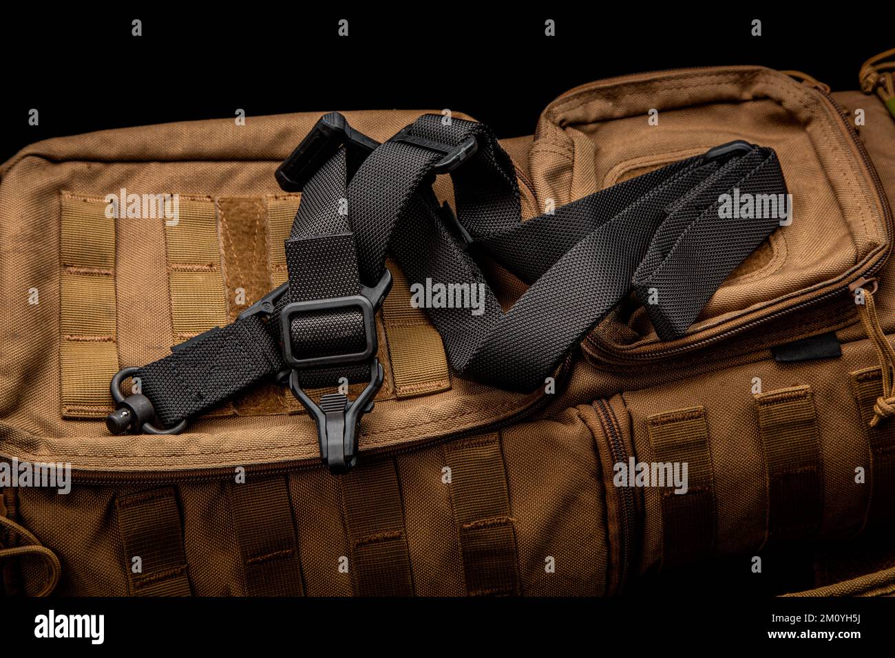 A black nylon weapon belt on a brown military backpack. Dark background ...